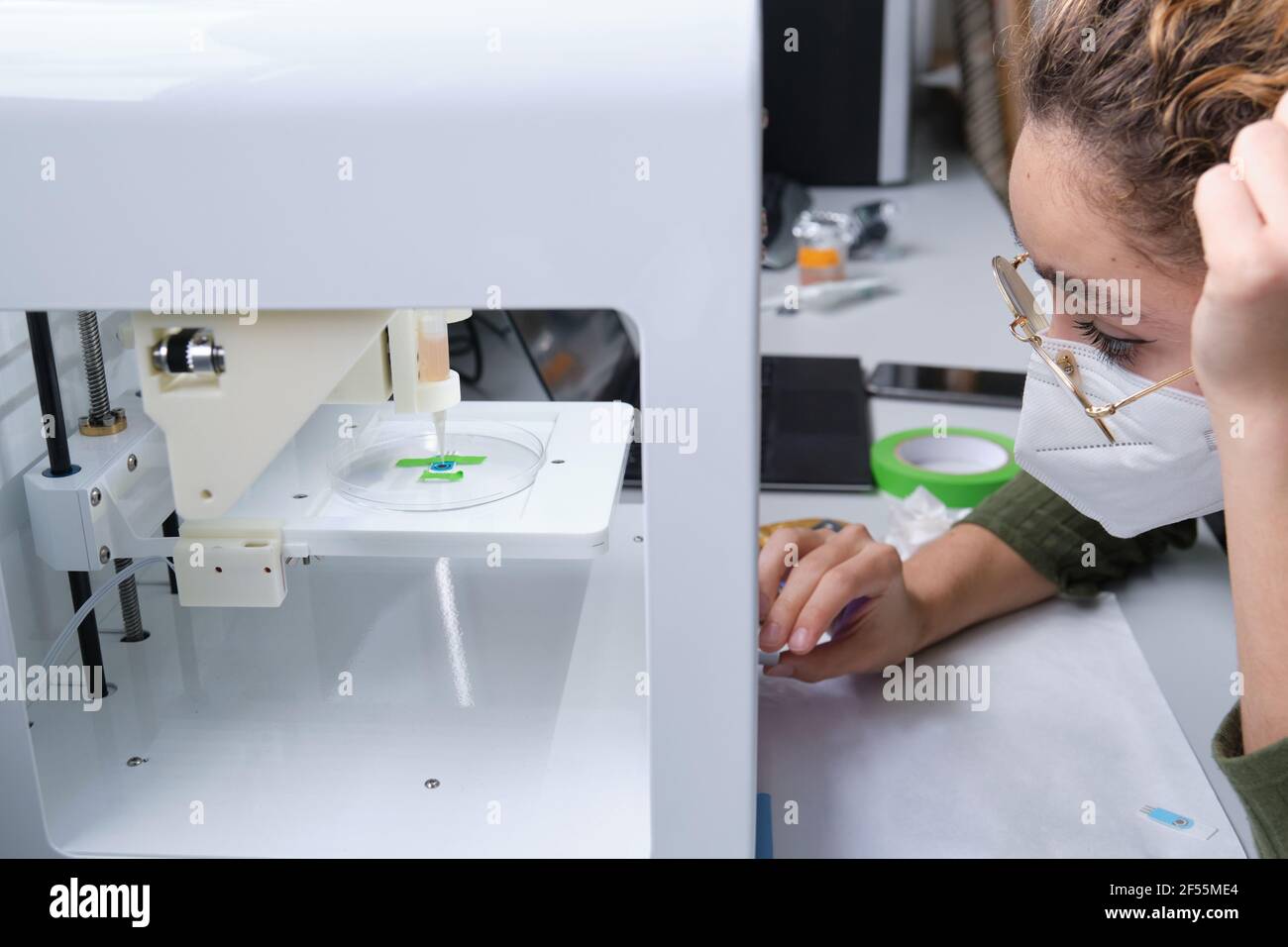 Researcher adjusting a 3D bioprinter to 3D print cells onto an ...