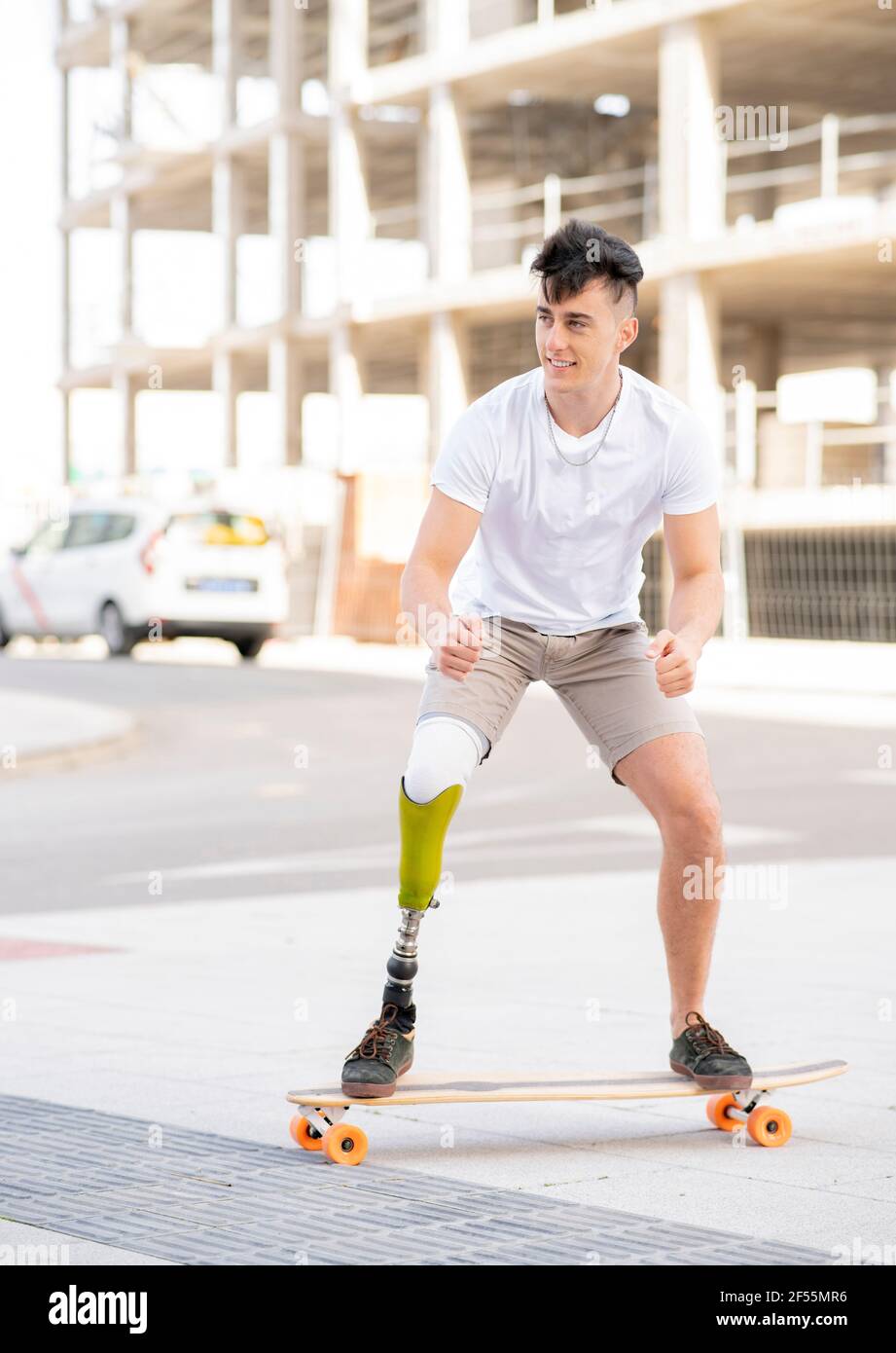 Smiling amputated man skateboarding on street Stock Photo - Alamy