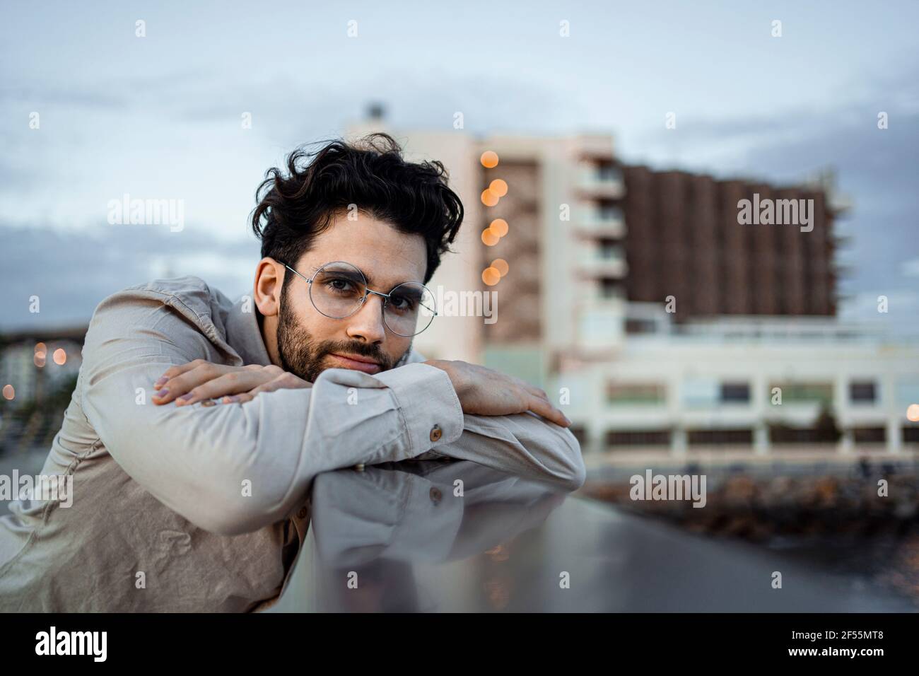 Handsome male entrepreneur with arms crossed leaning on railing Stock ...