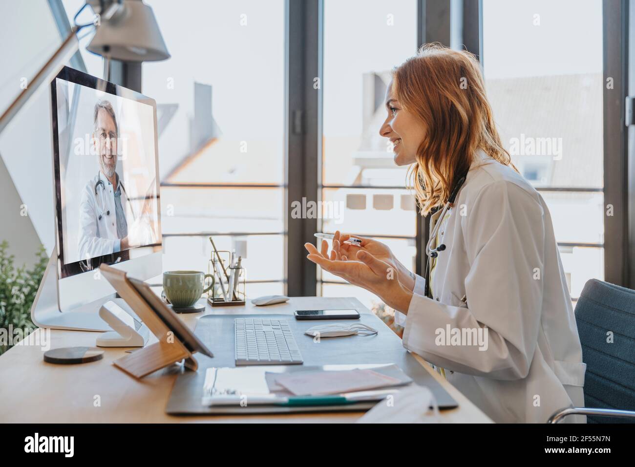 Healthcare worker talking to coworker on video call over computer while ...