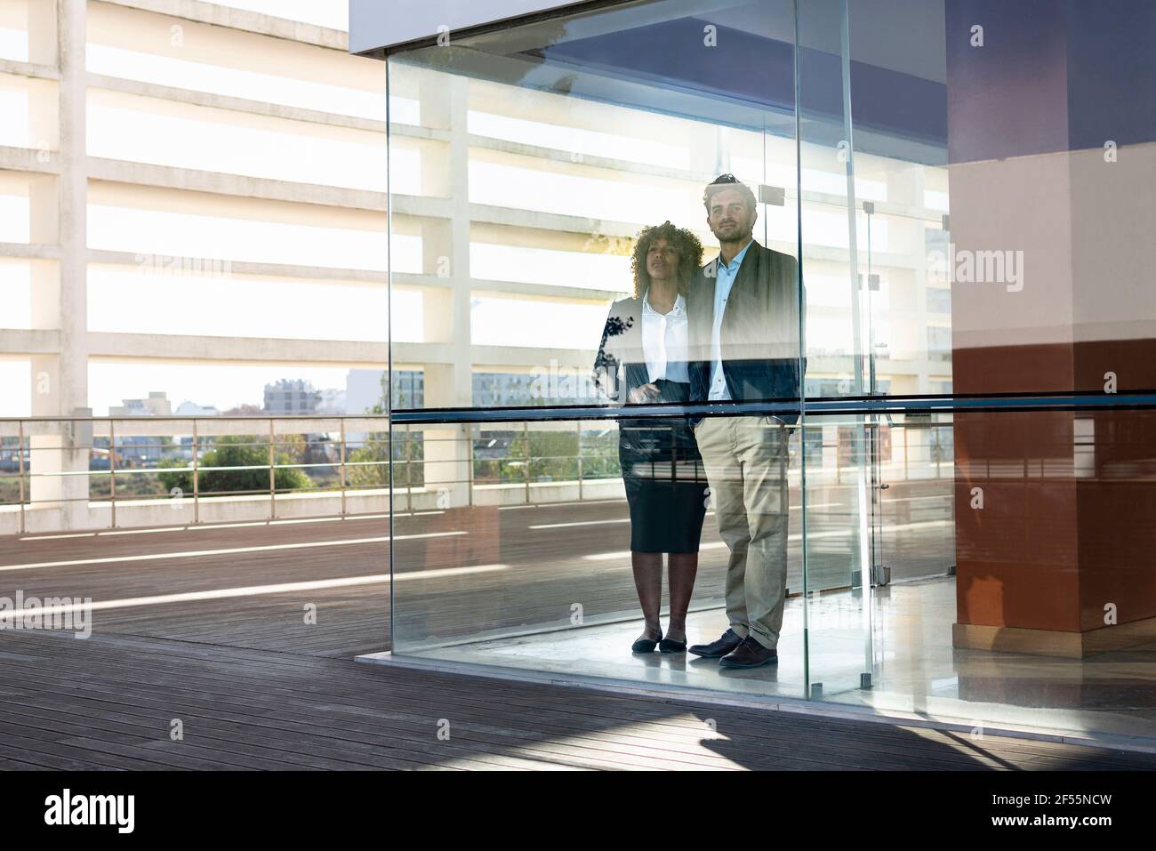Entrepreneurs looking through window while standing in modern office ...