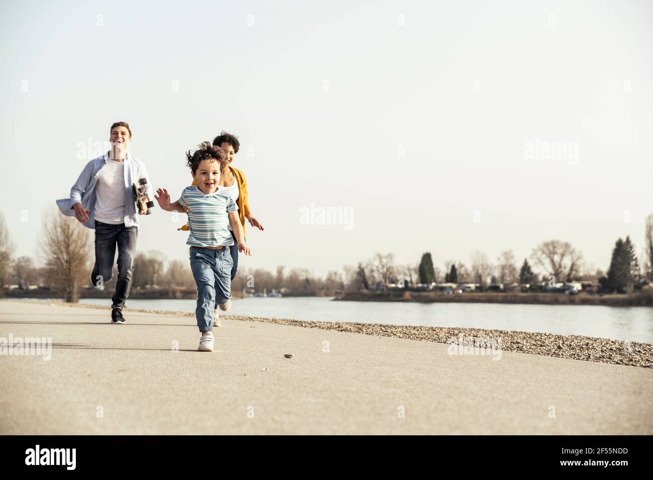 Happy son running with parents in background on road Stock Photo - Alamy