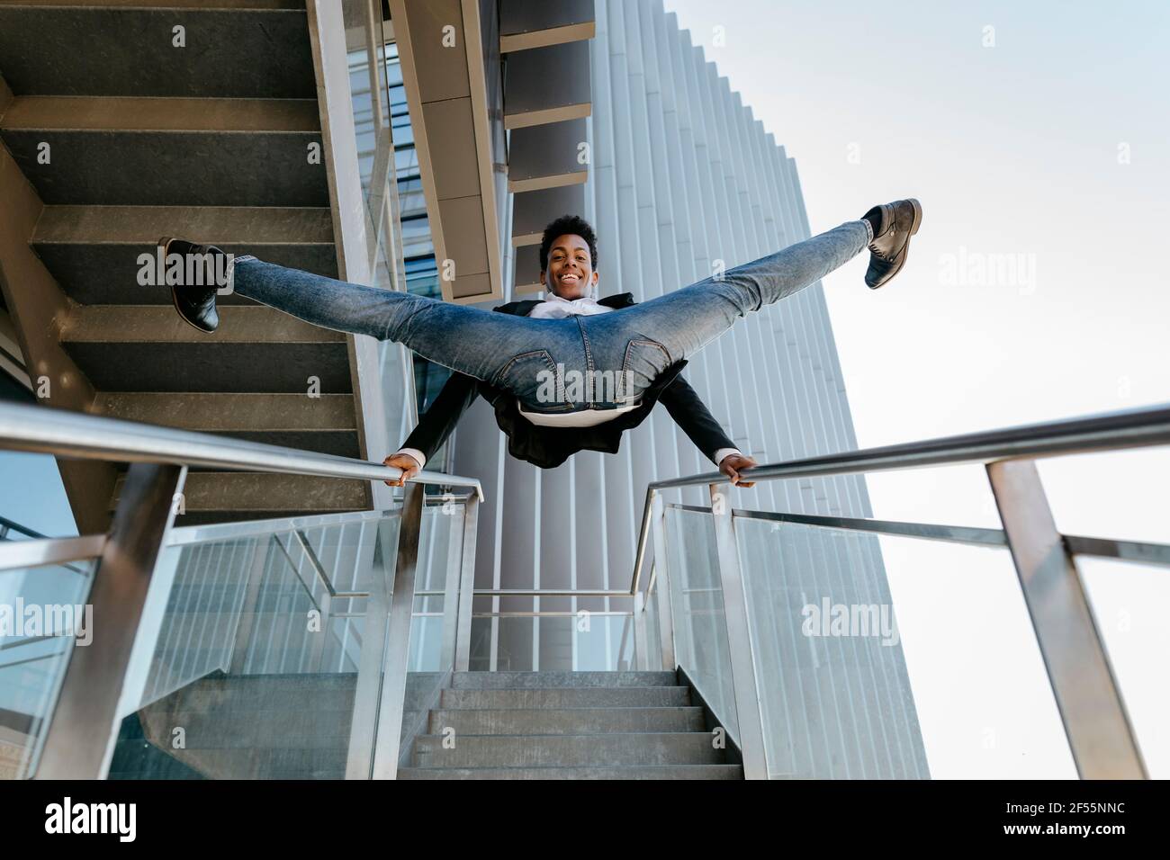 Happy male professional doing splits on staircase railing Stock Photo ...
