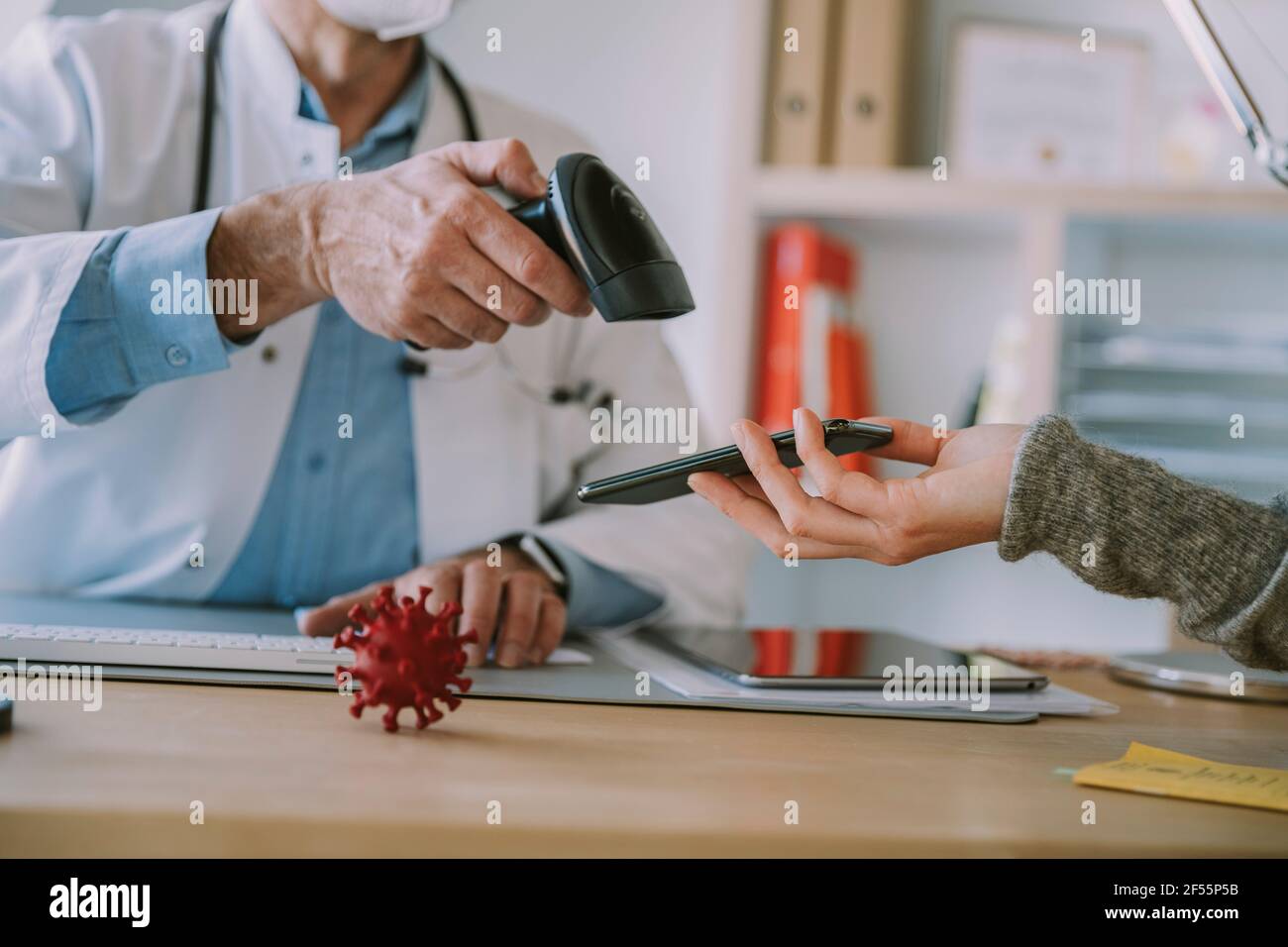 Doctor scanning patient mobile phone through handheld scanner while ...