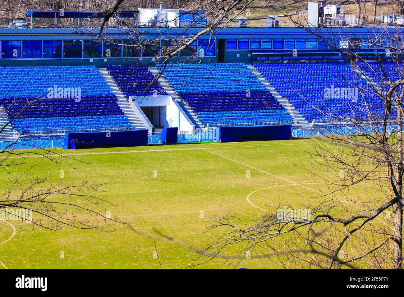 An open deserted soccer stadium with bright green grass, rows of blue ...