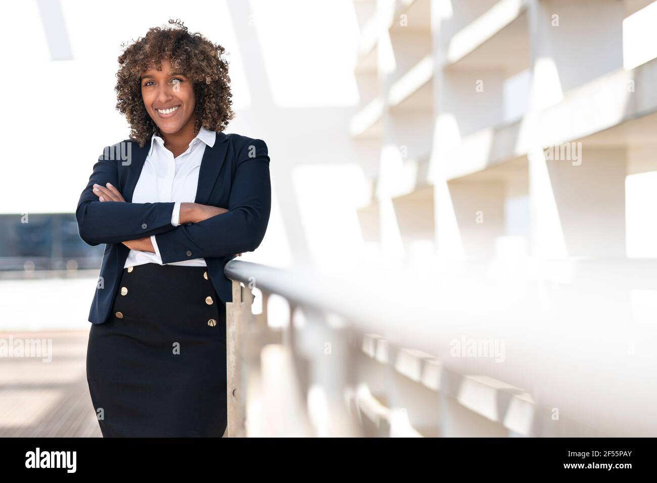 Confident female professional smiling while standing with arms crossed ...