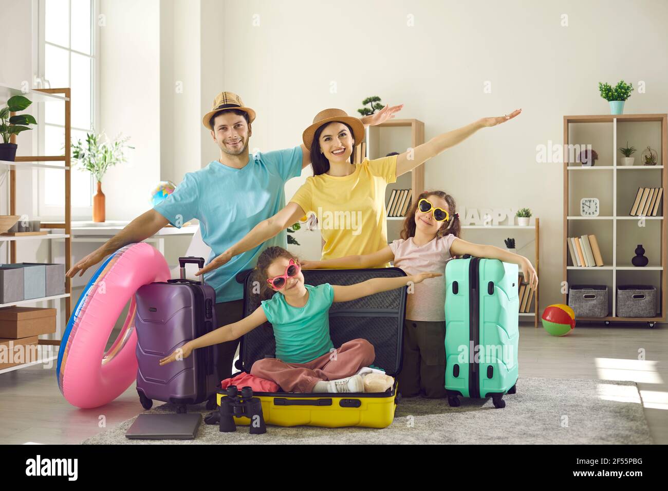 Portrait of happy family ready for holiday trip pretending to fly like ...