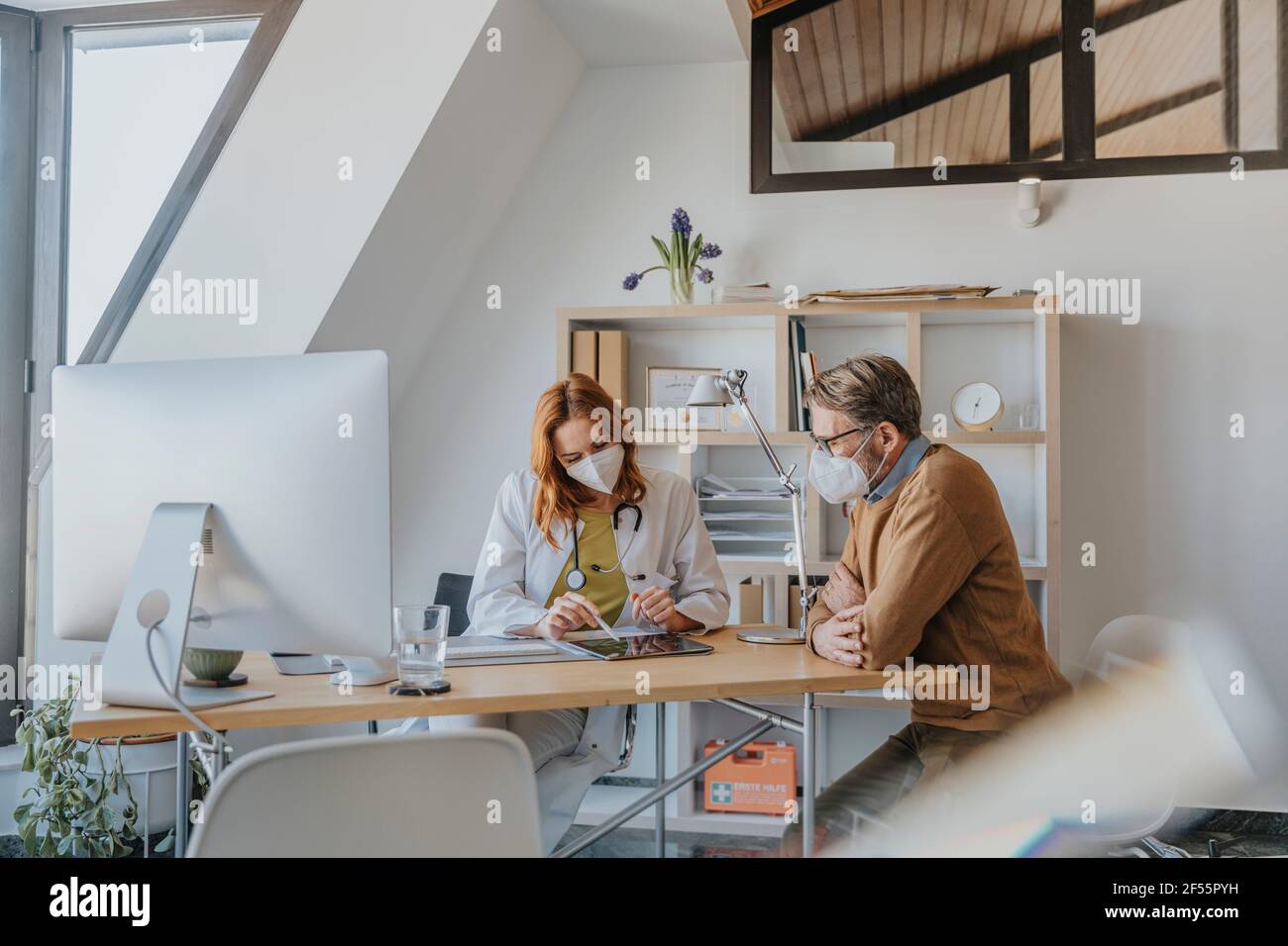 Female general practitioner explaining patient over digital tablet at ...
