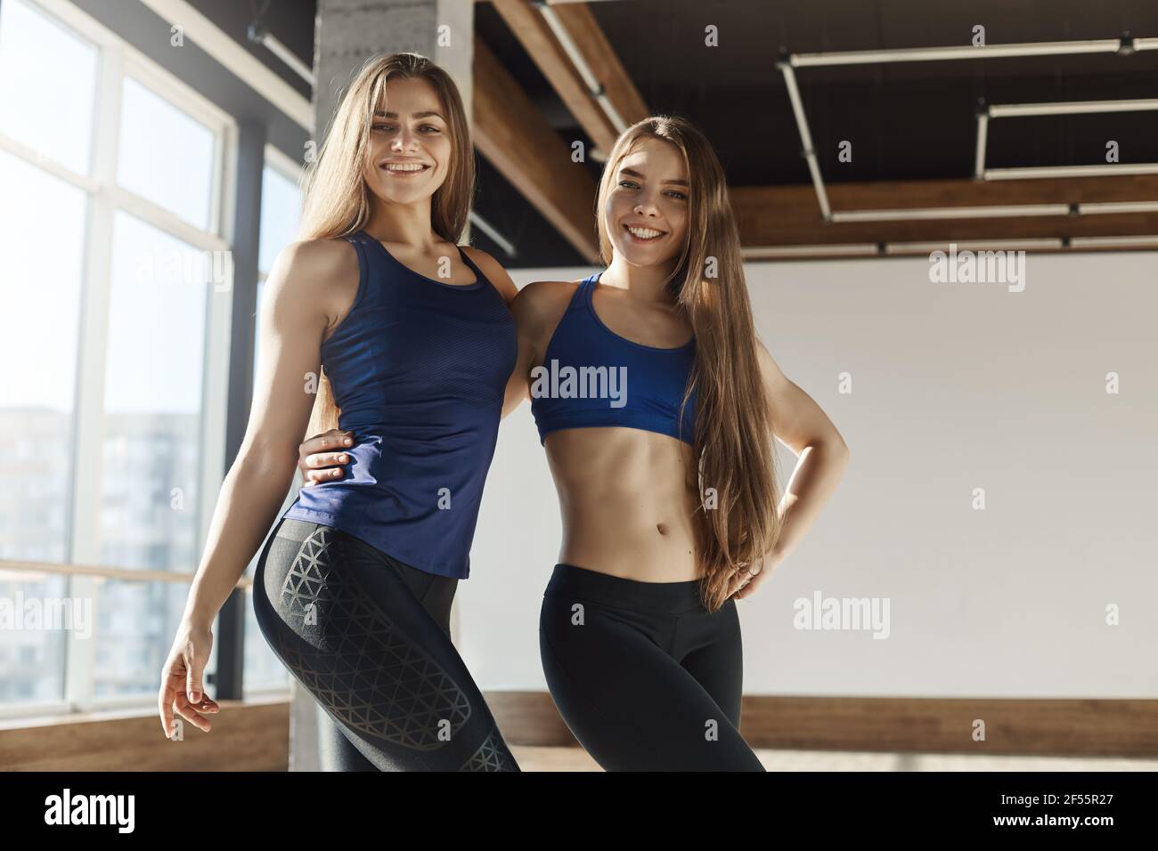 Two active and healthy female fitness instructors embracing gym class ...