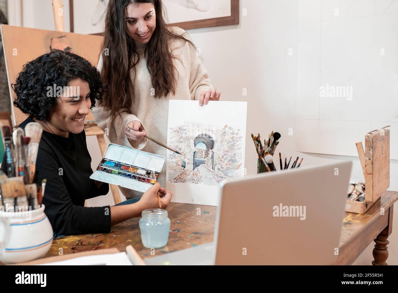Female artists showing painting during video call at studio Stock Photo ...