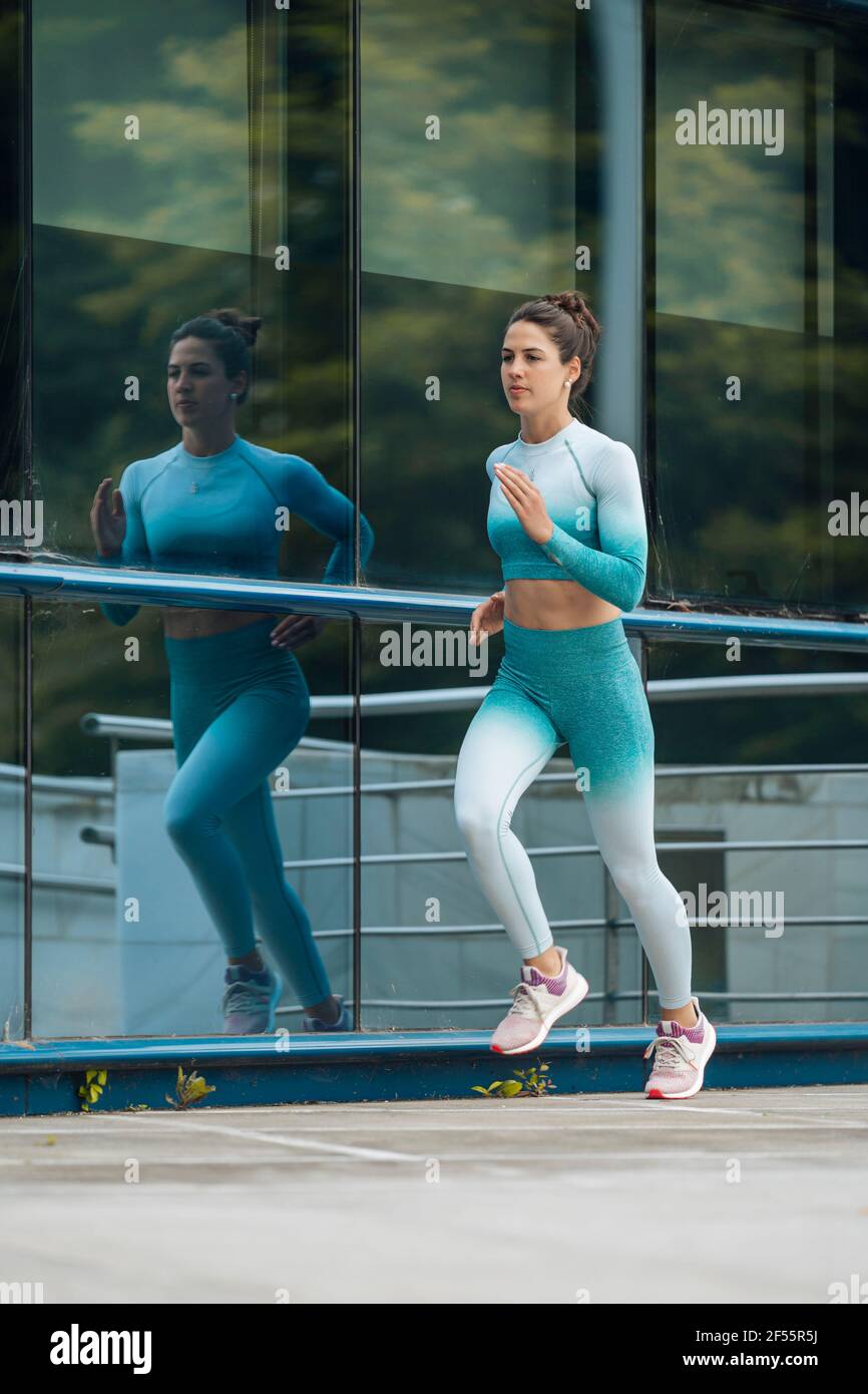 Determinant sportswoman running on footpath by glass wall Stock Photo ...