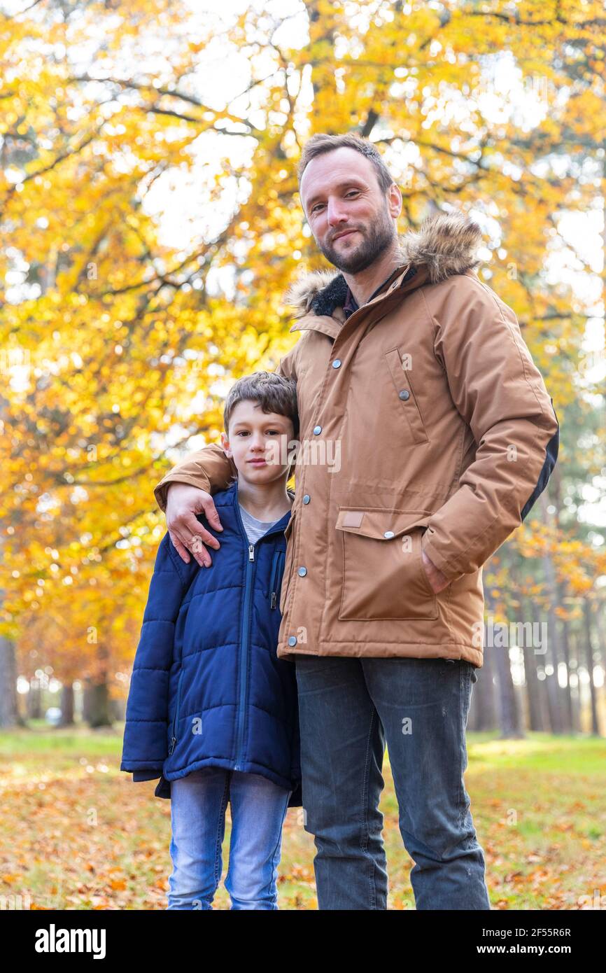Father and son smiling while standing together in forest Stock Photo ...