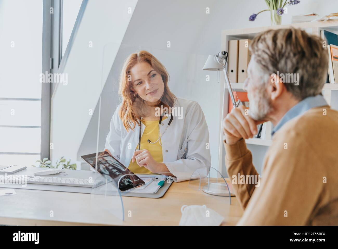 Female doctor explaining patient over x-ray while sitting by screen ...