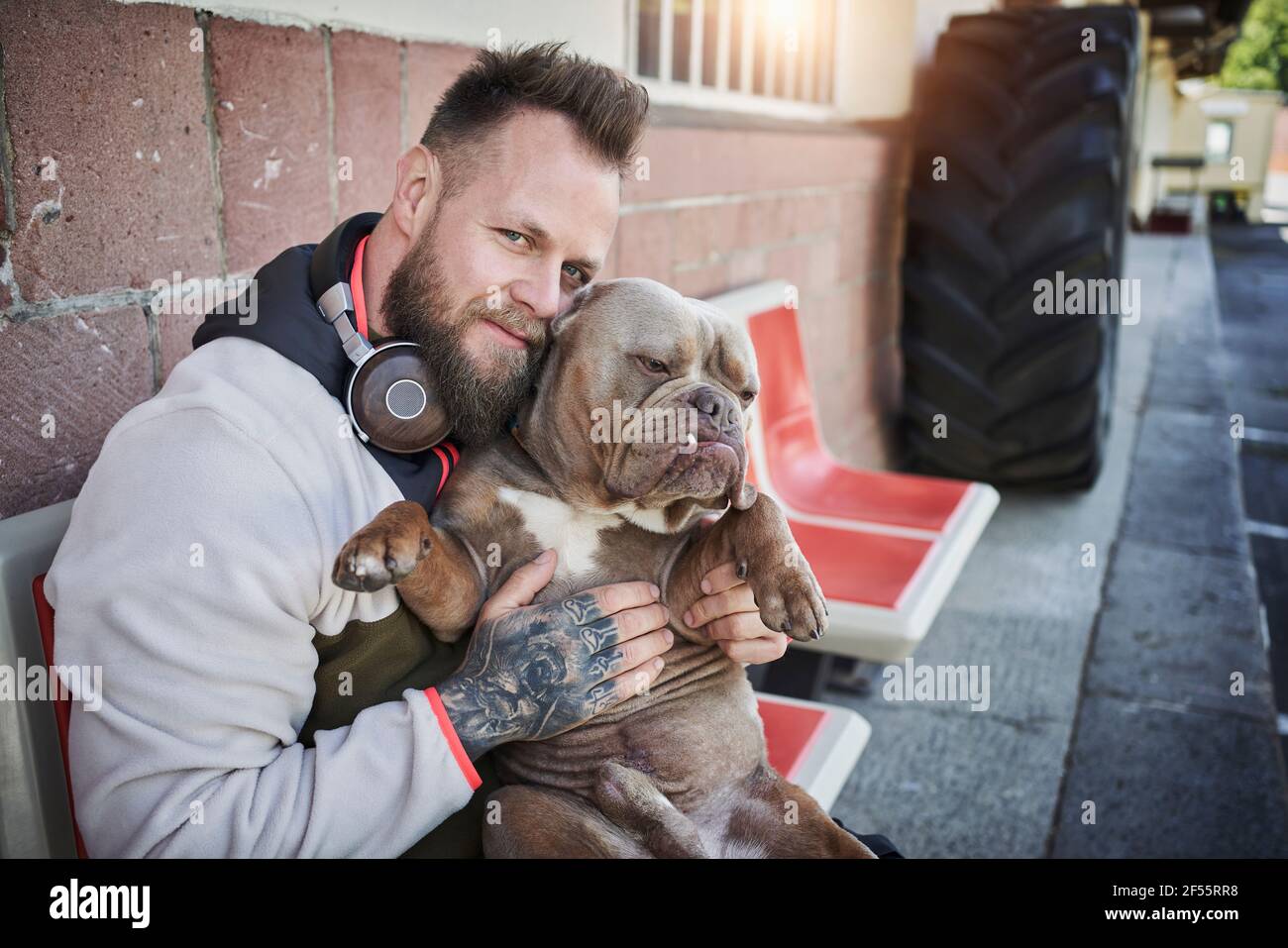 Male fitness instructor embracing bulldog outside gym Stock Photo - Alamy