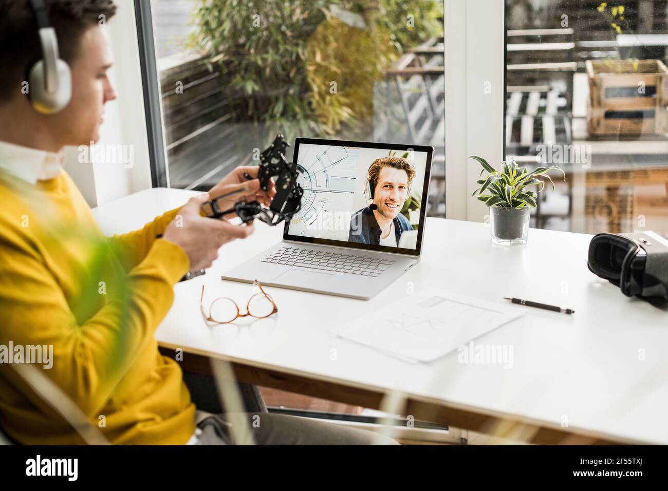 Young male engineer giving presentation about robotic arm through video ...