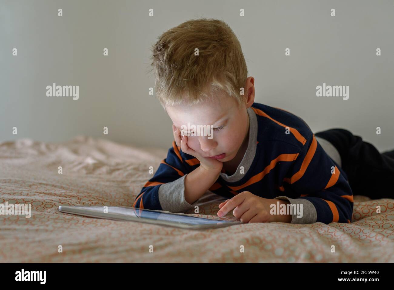 Little Boy using tablet laying in bed. Boring Stock Photo - Alamy