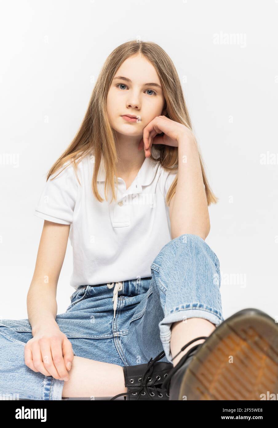 Girl sitting with hand on cheek against white background Stock Photo ...