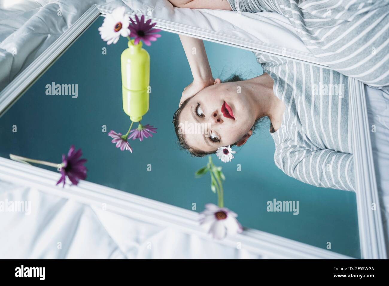 Young woman reflecting in mirror lying on bed Stock Photo - Alamy