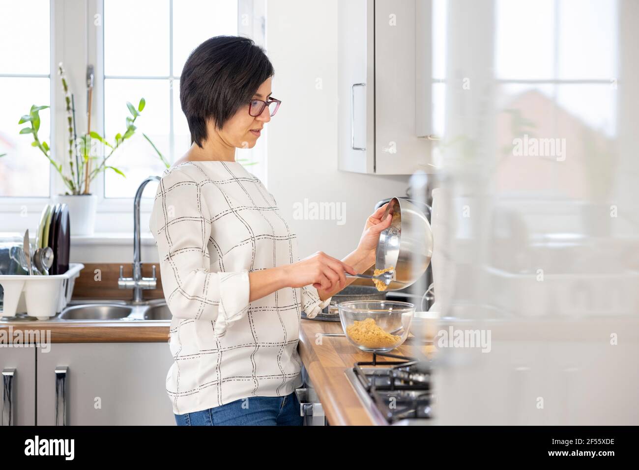 Woman crumbling biscuits to bake a cheesecake Stock Photo - Alamy