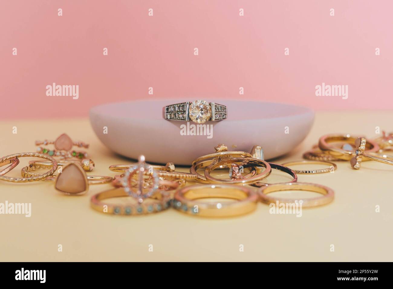 Shiny gold and silver jewellery on pastel pink and yellow background ...