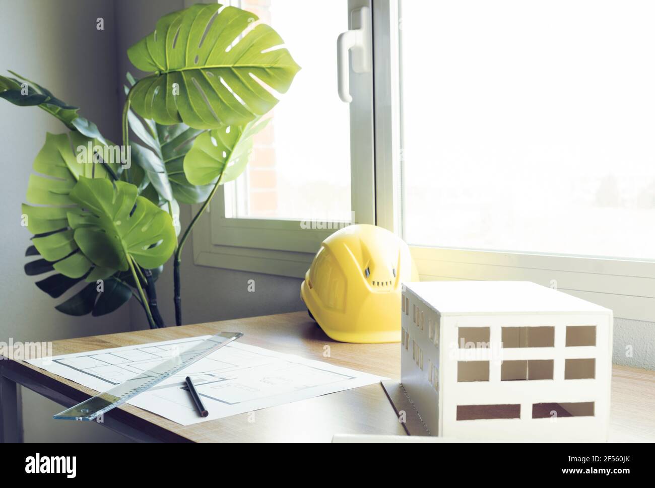 Architectural model with paper and hardhat on desk against window in ...