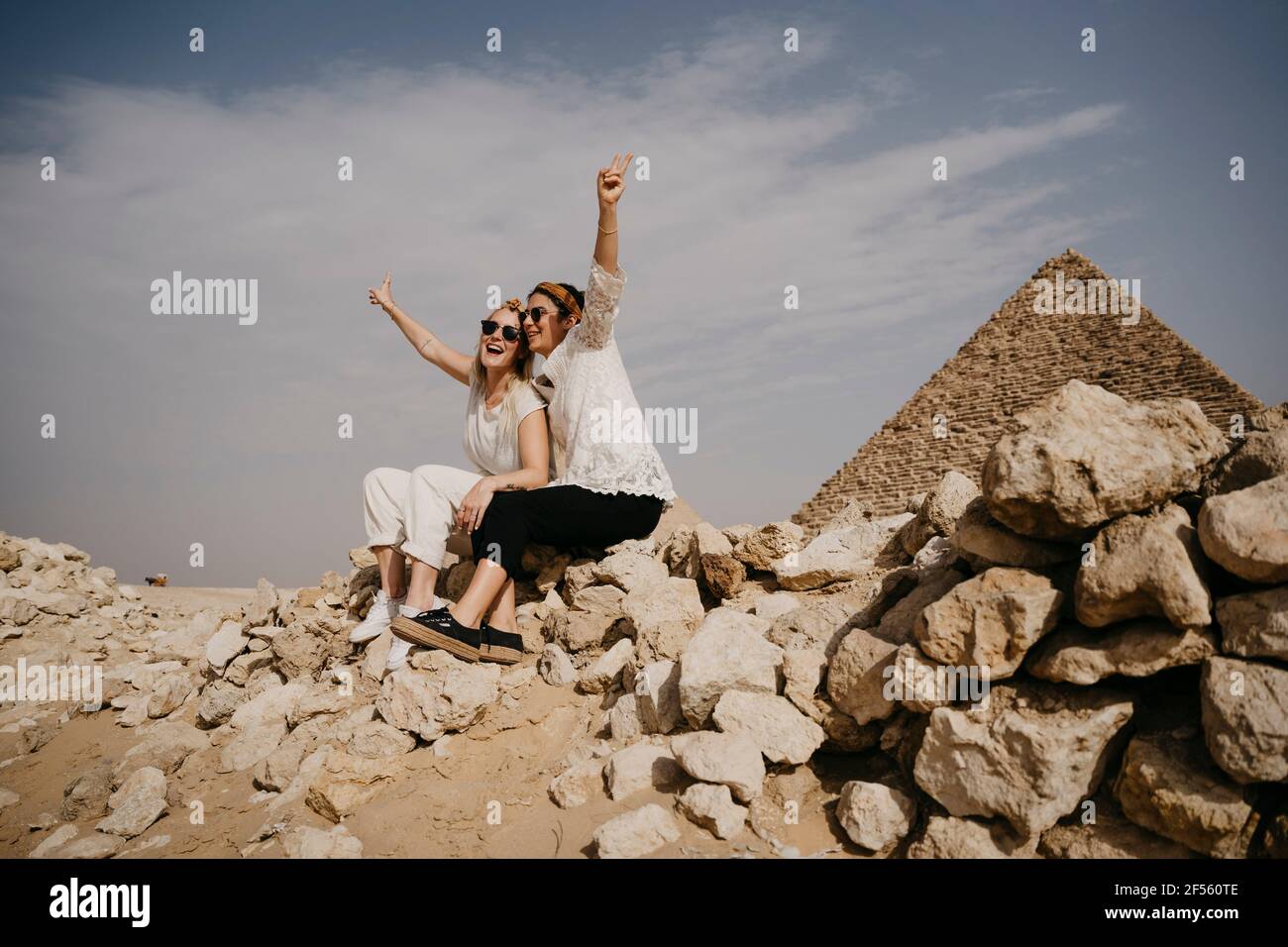 Egypt, Cairo, Two female tourists sitting together on rocks with Great ...