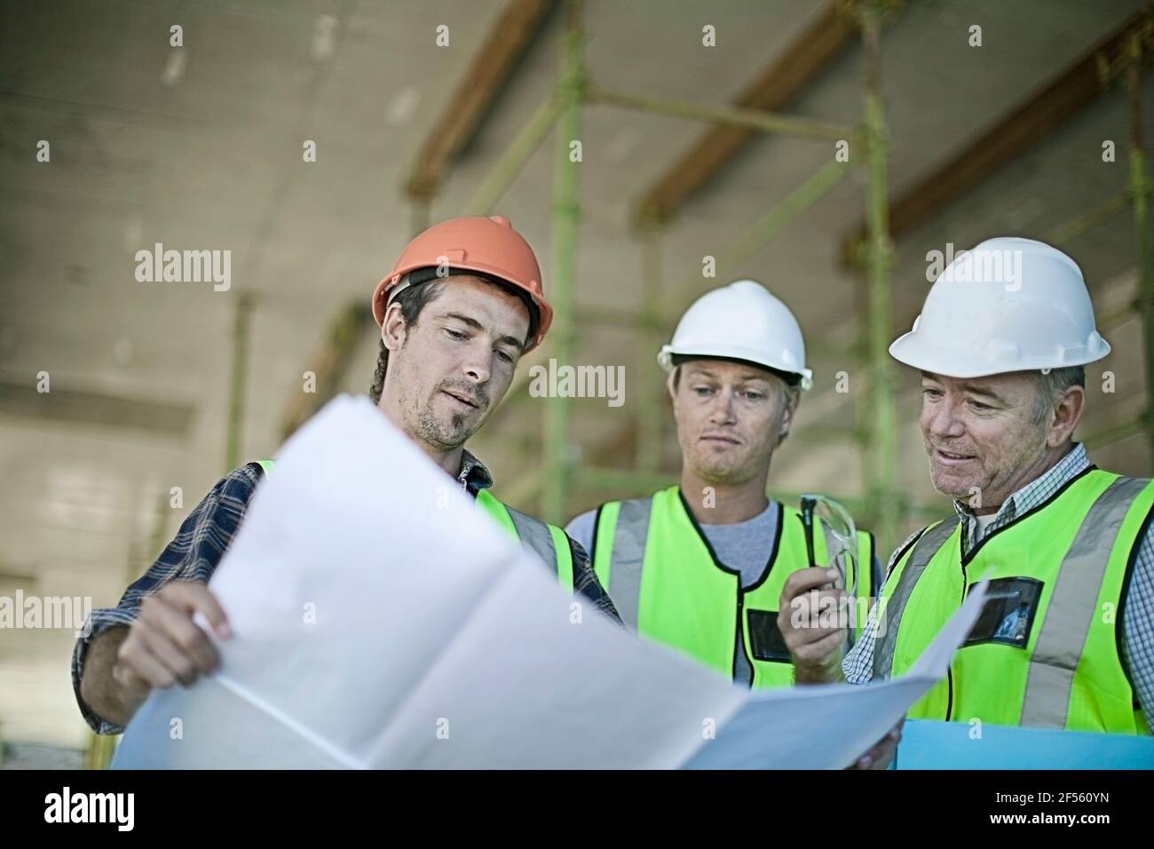 Male construction workers talking over plans at construction site Stock ...