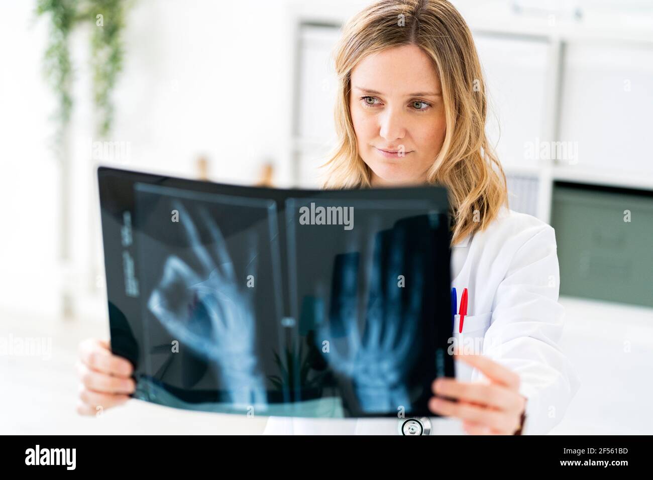 Blond female radiologist analyzing X-ray at medical clinic Stock Photo ...