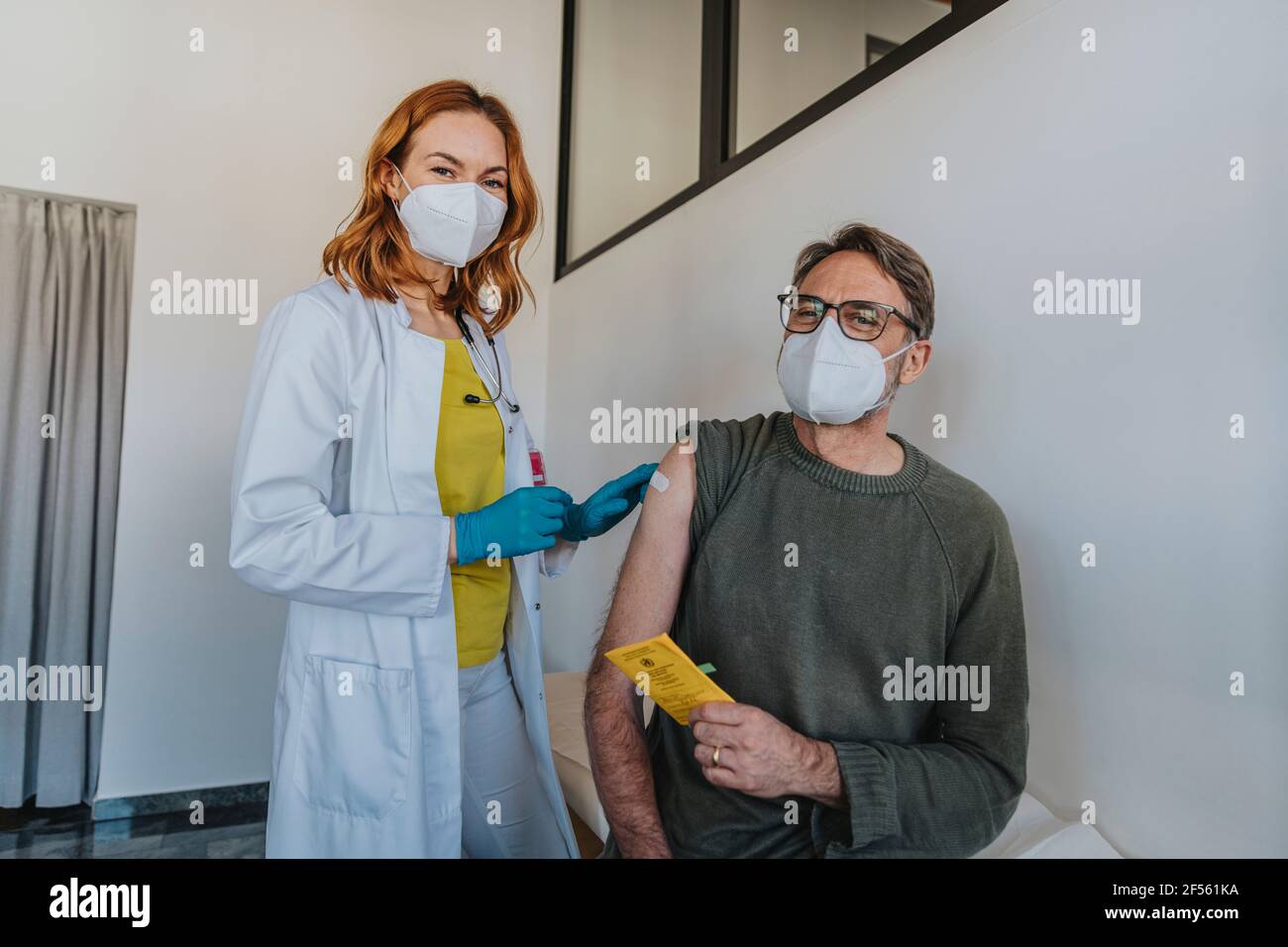 Doctor wearing protective face mask putting bandage while standing by ...