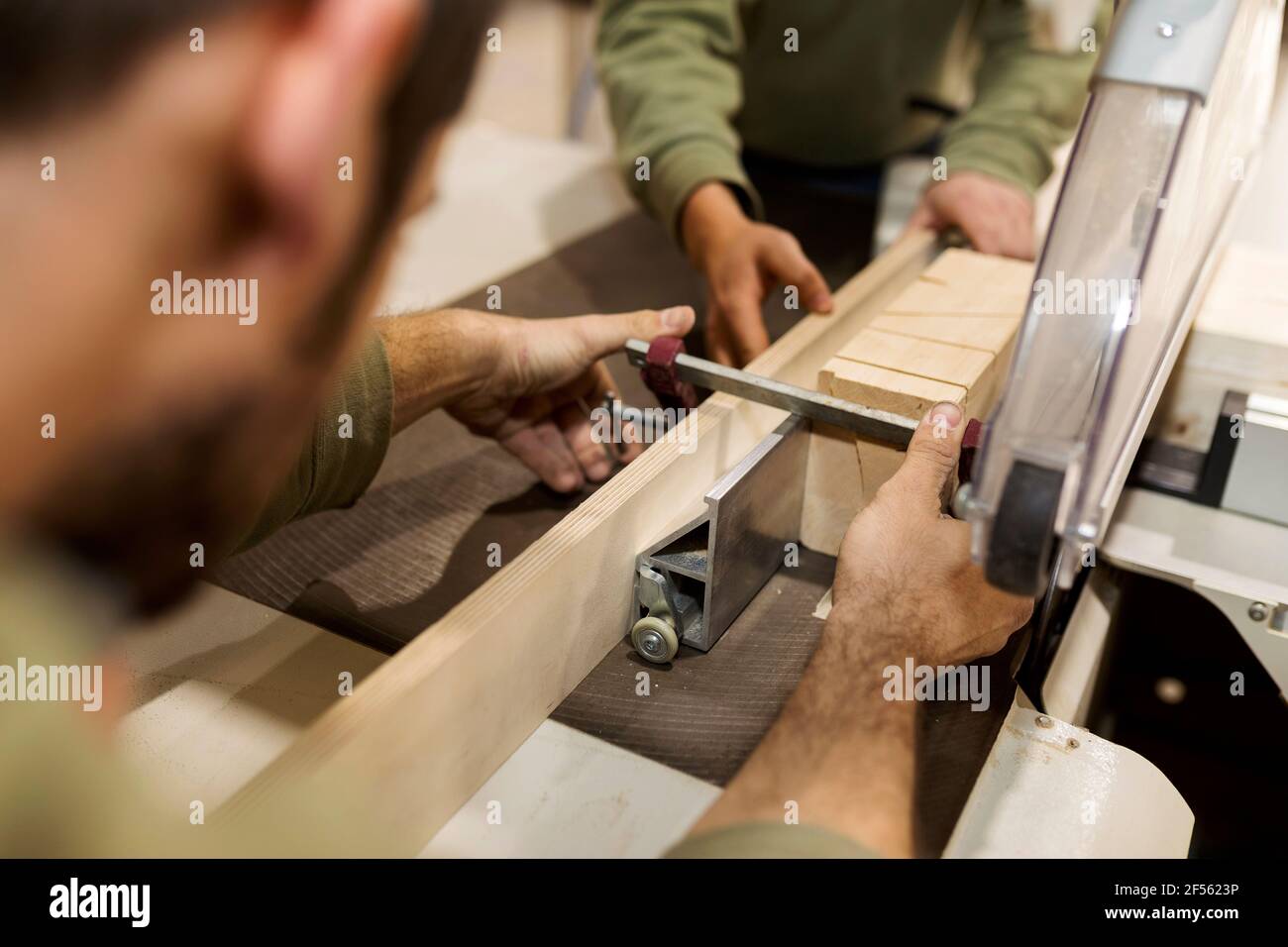 Male carpenters working with carpentry equipment at workbench in ...