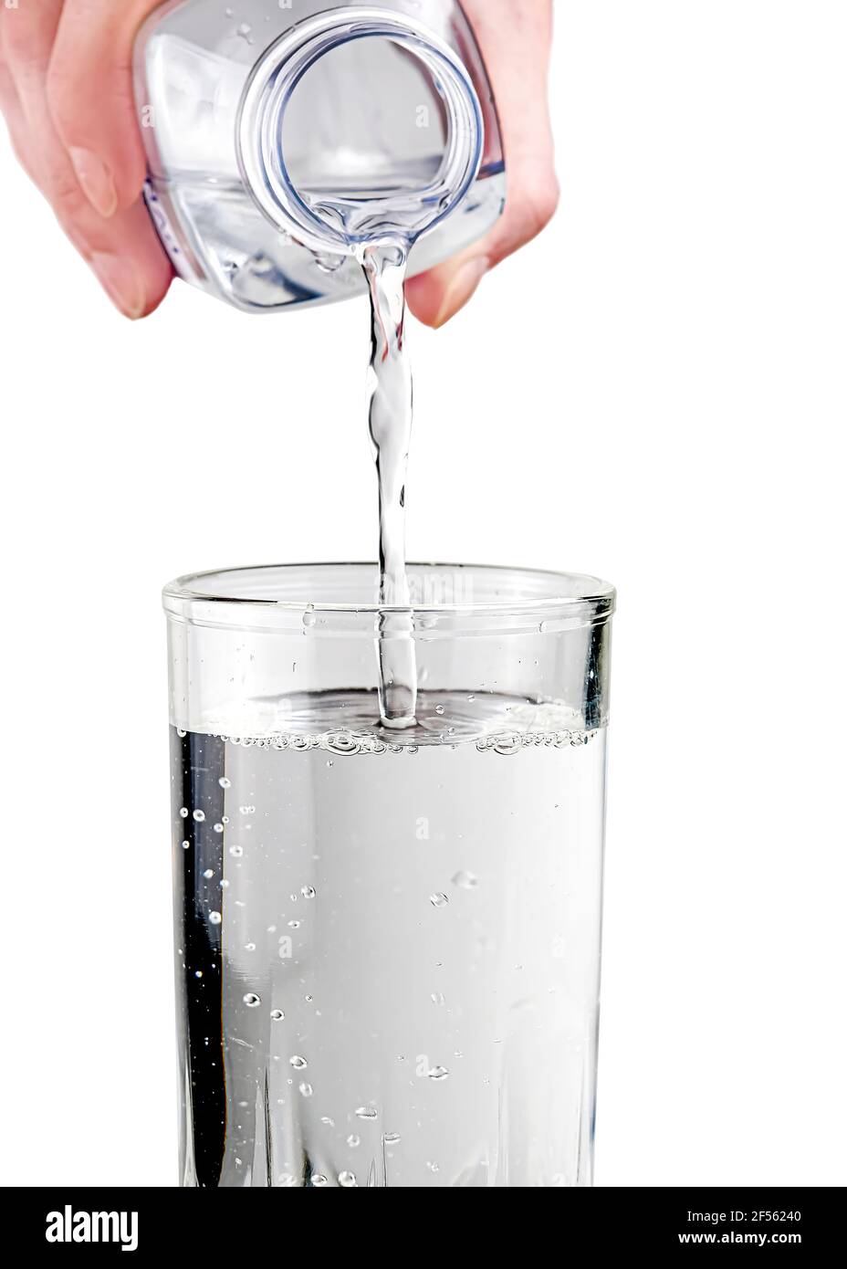 Pouring water from a bottle on glass on a light background. Natural ...