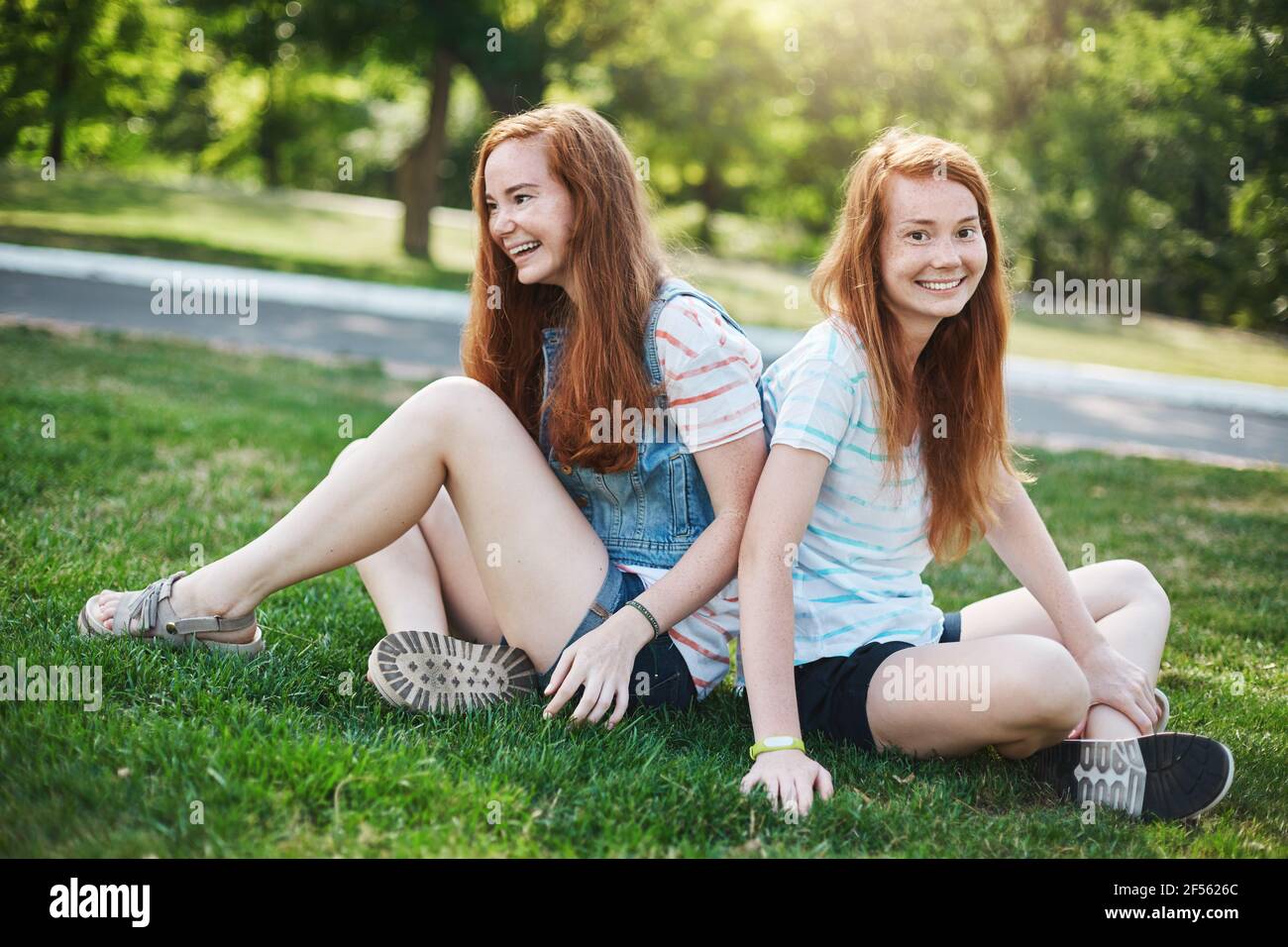 Pair of identical twins ginger sisters having fun outdoor in the park ...