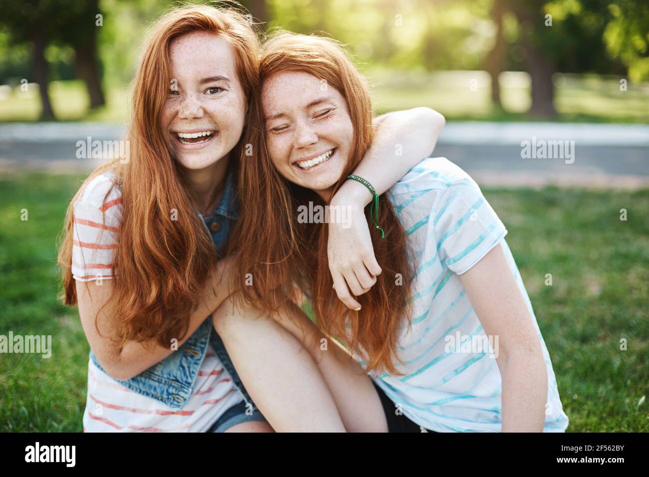 Wanna hug her forever. Portrait of happy and carefree two twin sisters with natural red hair and ...
