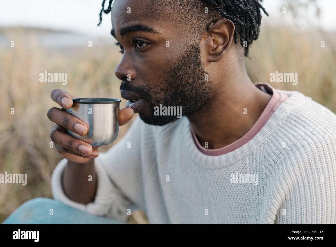 Young man drinking tea at beach Stock Photo - Alamy