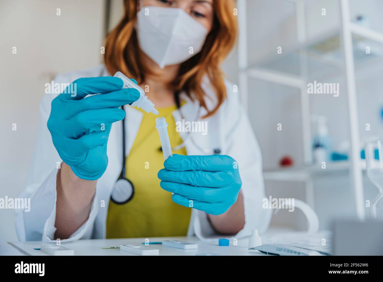 Doctor testing sample in test tube while sitting at examination room ...