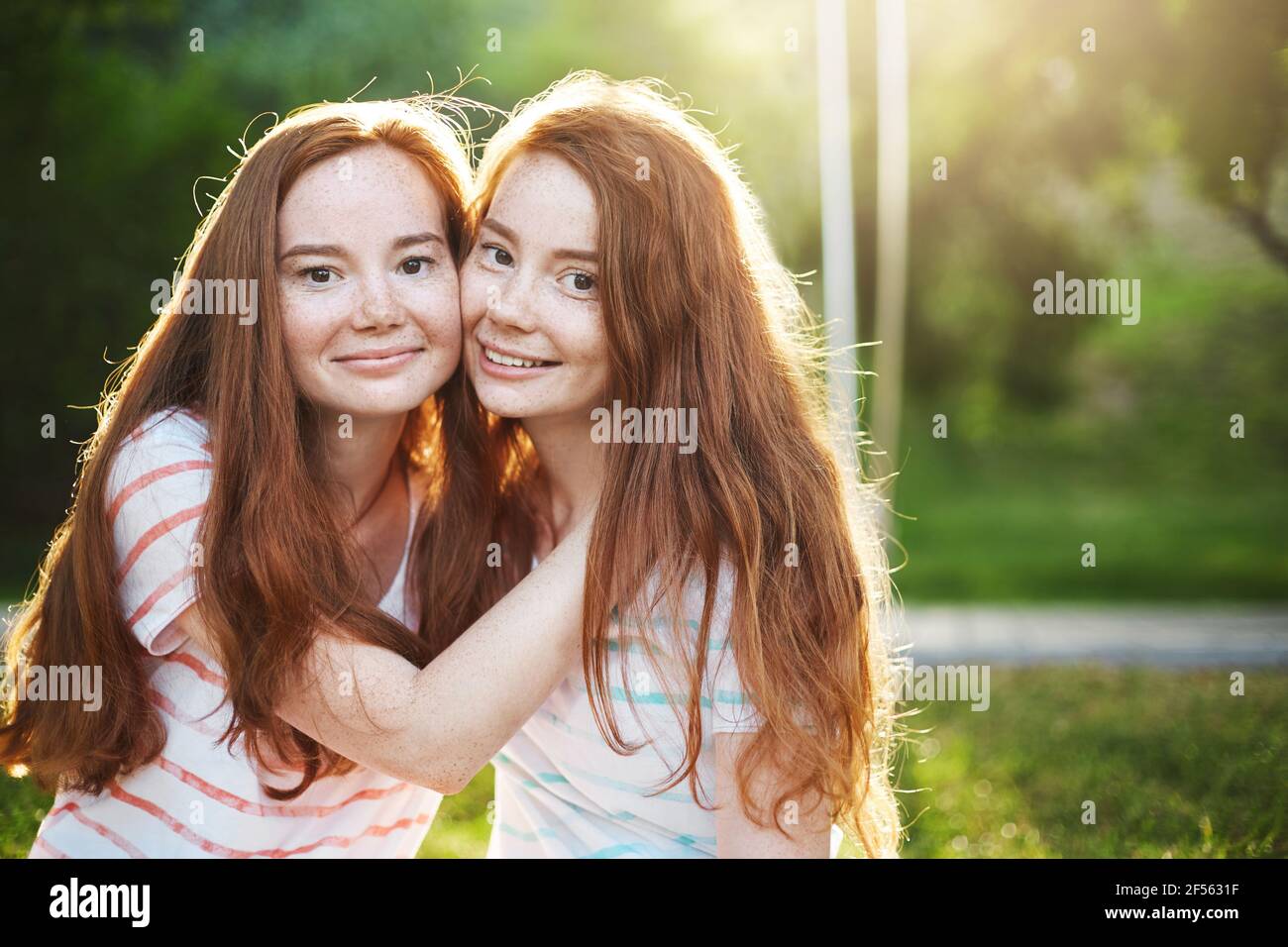 Twin ginger sisters are best friends forever. Young ladies looking at ...