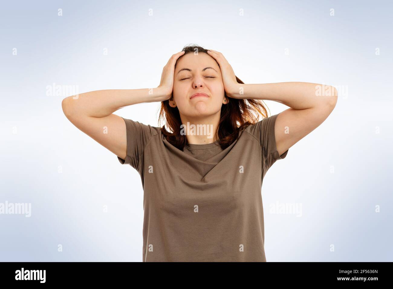 Migraines and headaches. Portrait of a young Caucasian woman clutching ...