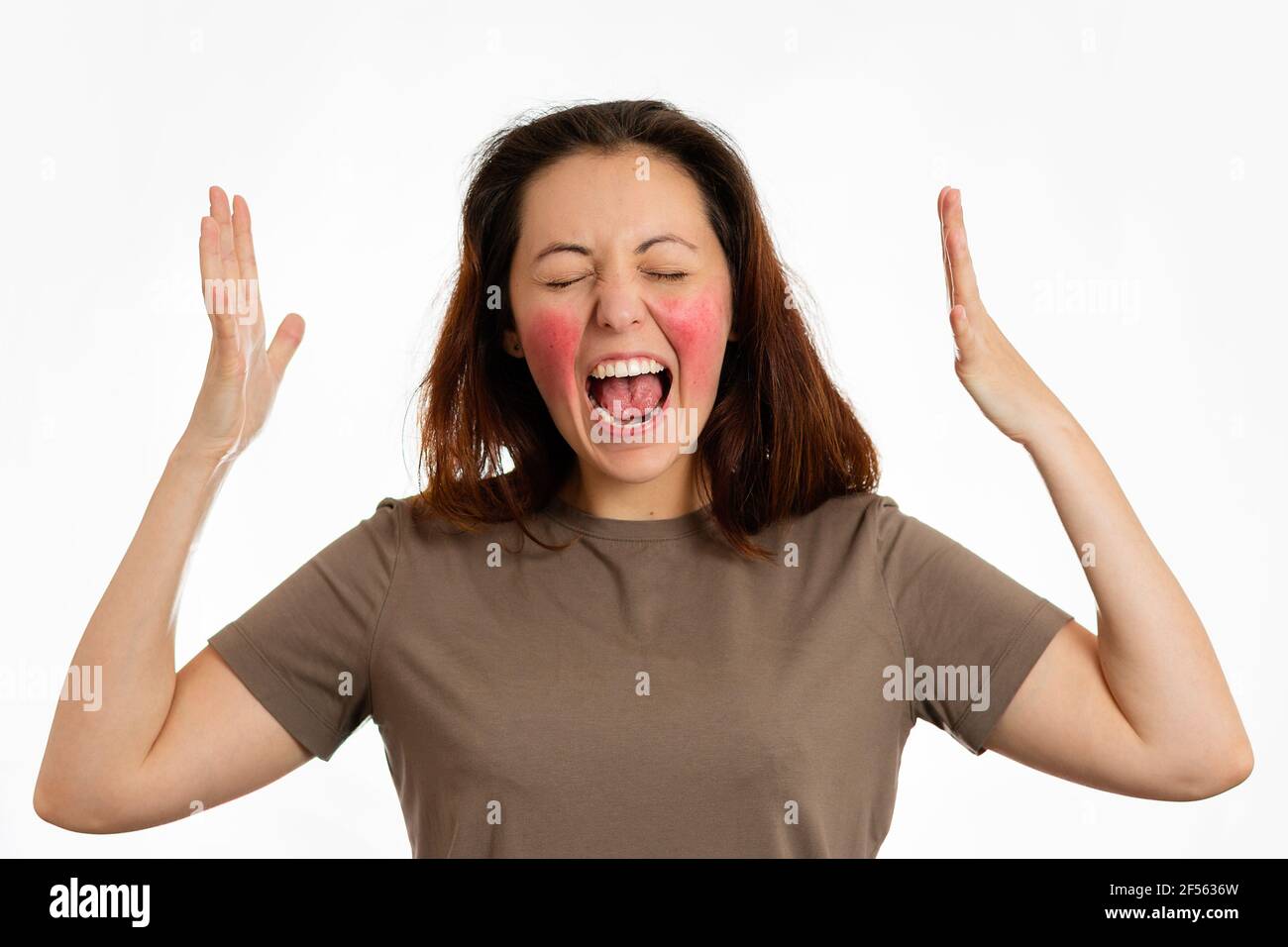 Portrait of a young screaming woman with red inflamed cheeks. White ...