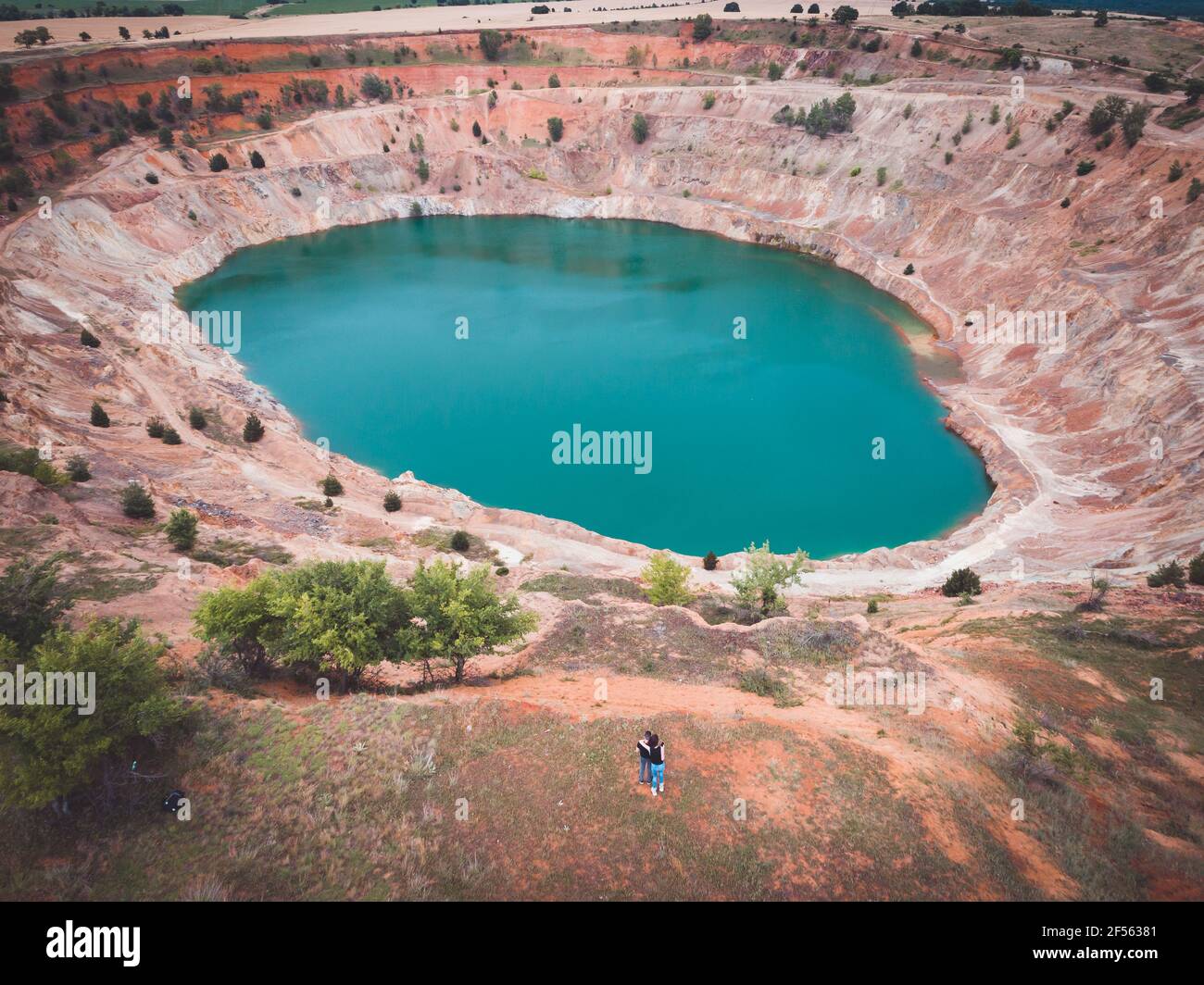 Aerial view of couple on travel adventure at abandoned open mine pit ...