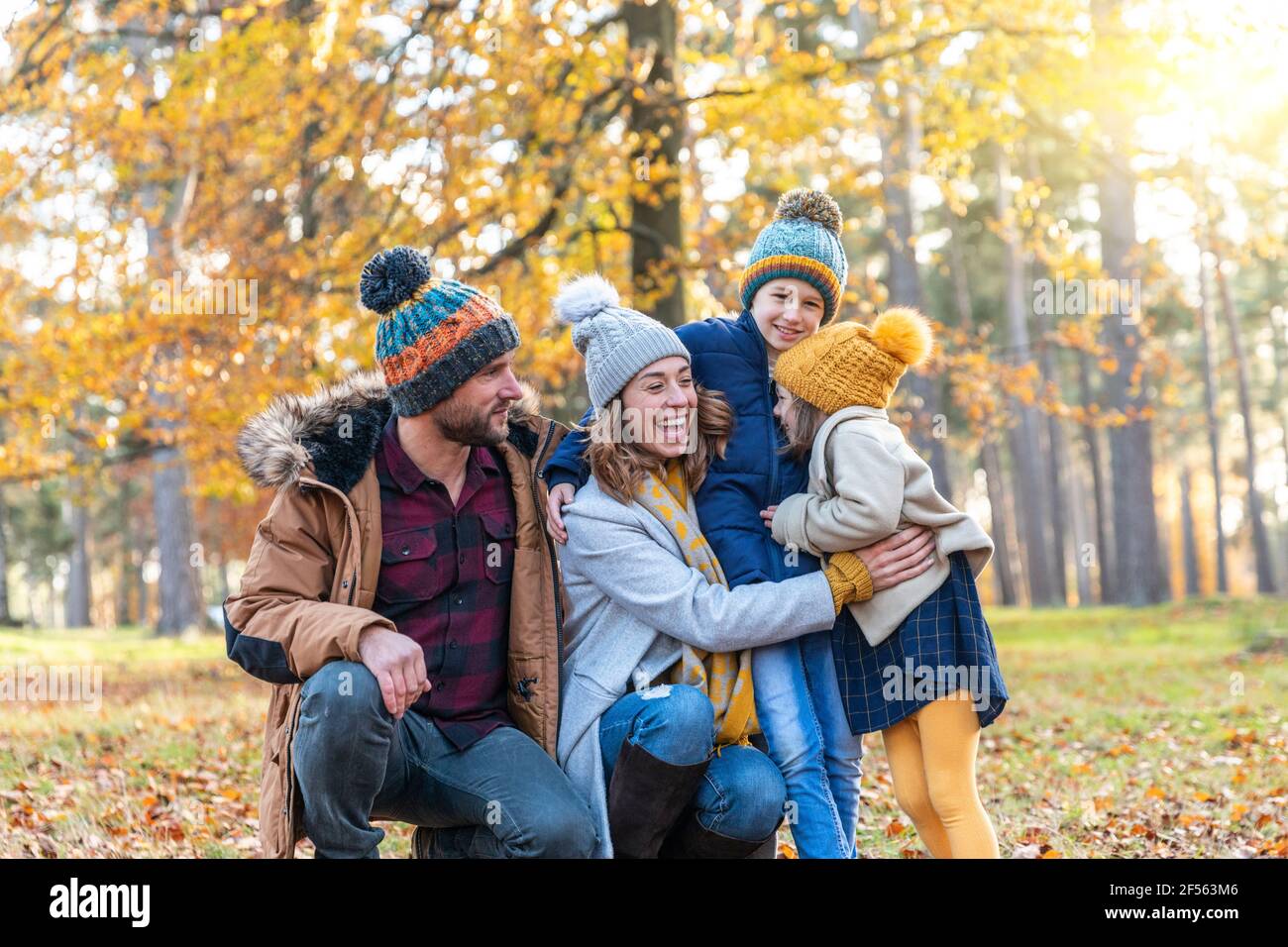 Mother embracing children while crouching by man in forest Stock Photo ...