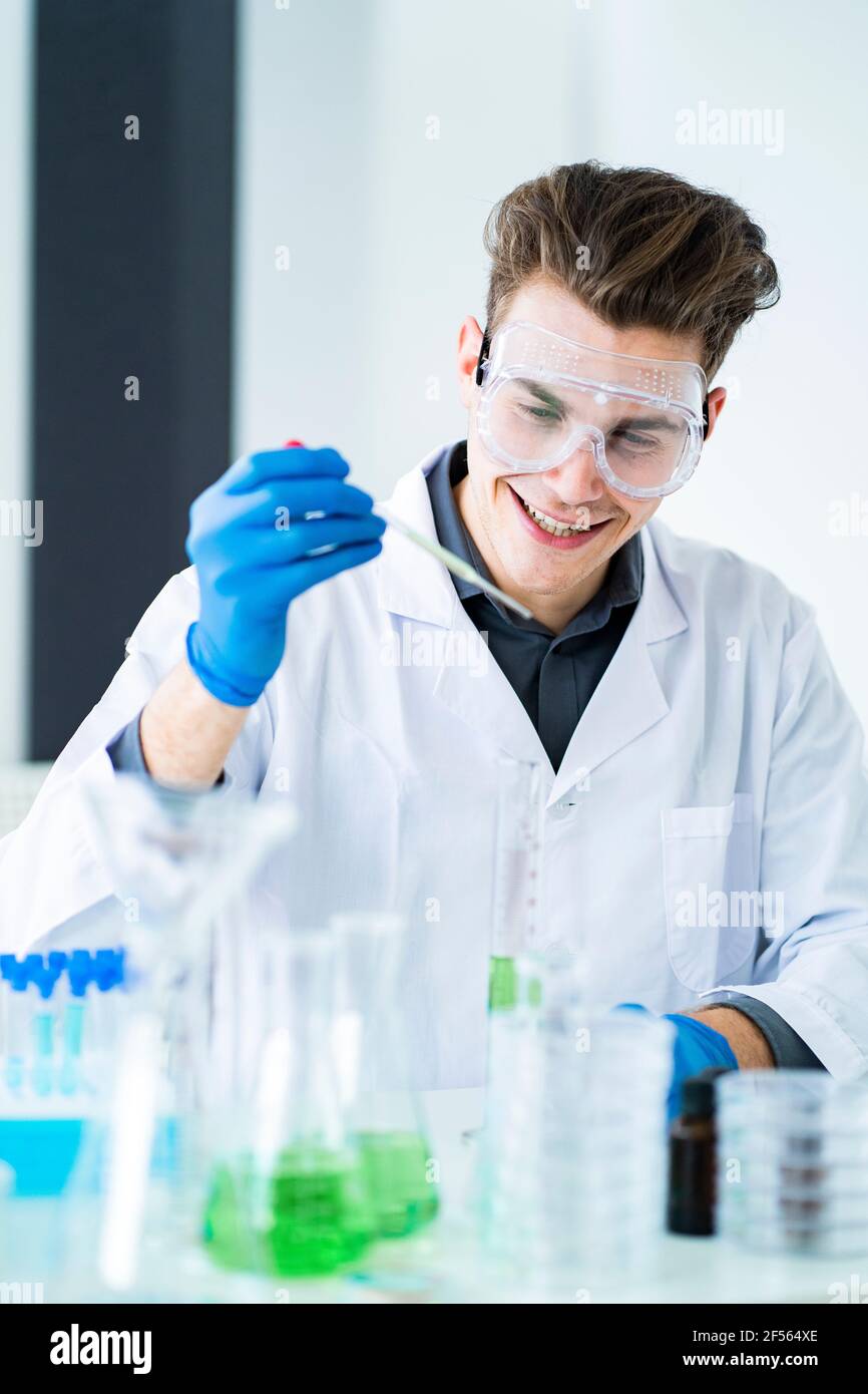 Smiling male scientist holding pipette while working in laboratory ...