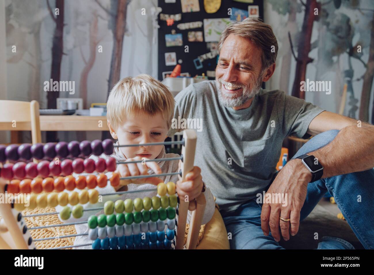 Happy father watching son counting abacus in bedroom Stock Photo - Alamy