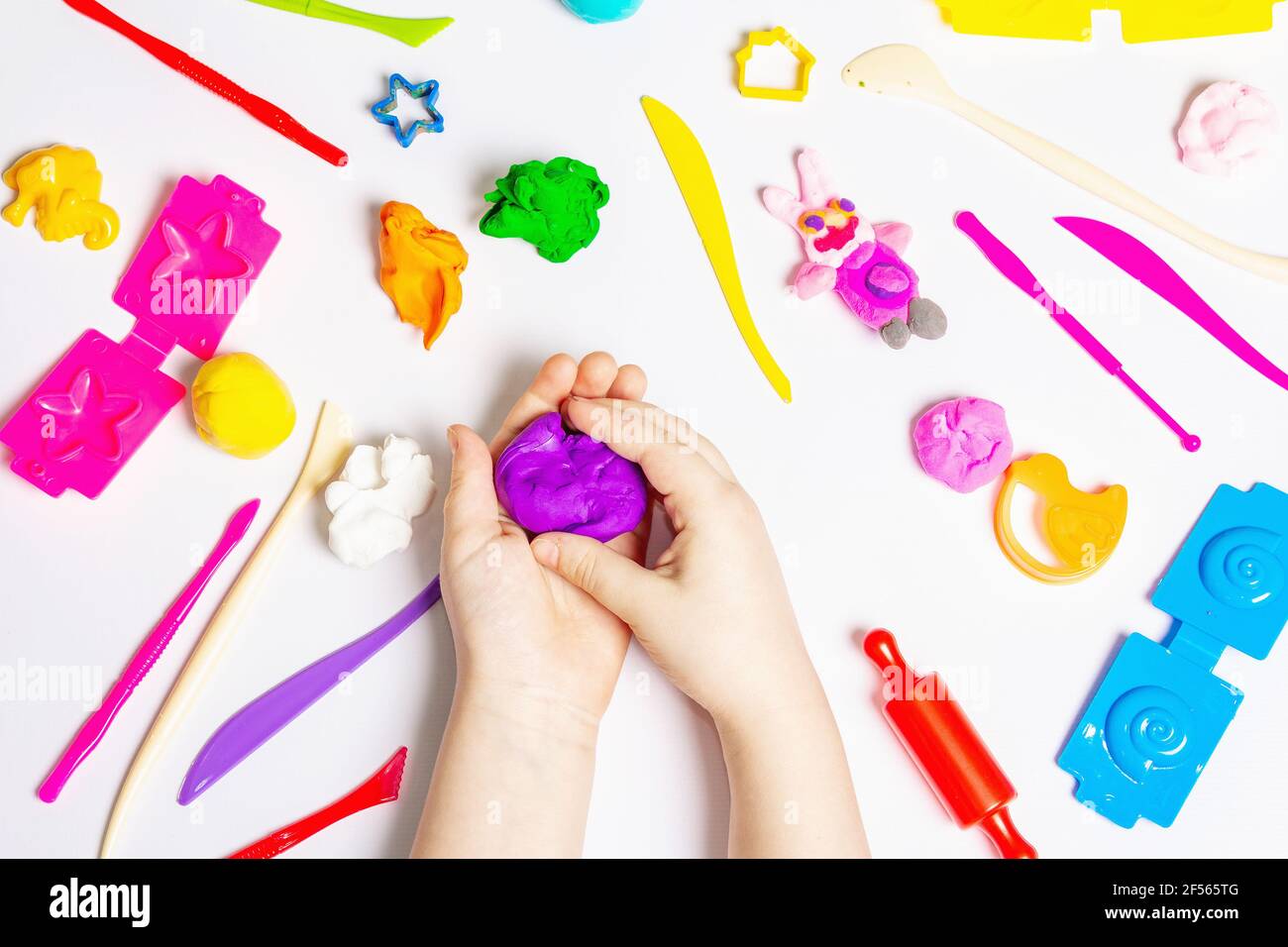 Children hands playing with colorful modeling clay on white background ...