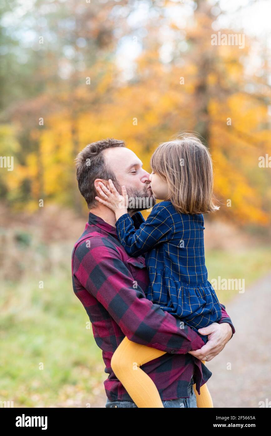 Father kissing daughter while standing in forest Stock Photo - Alamy