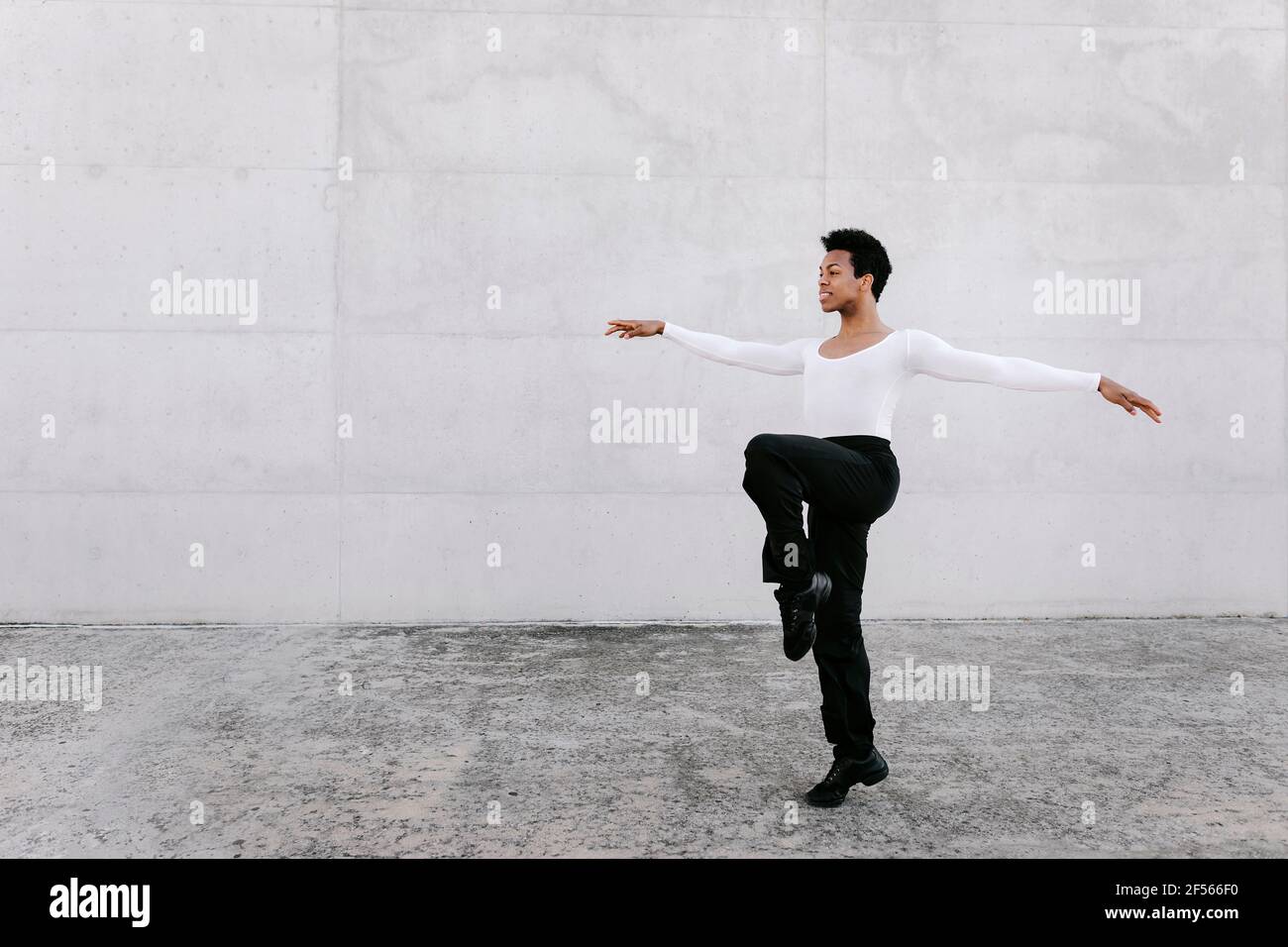 Urban dancer balancing on tiptoe while dancing against white wall Stock ...