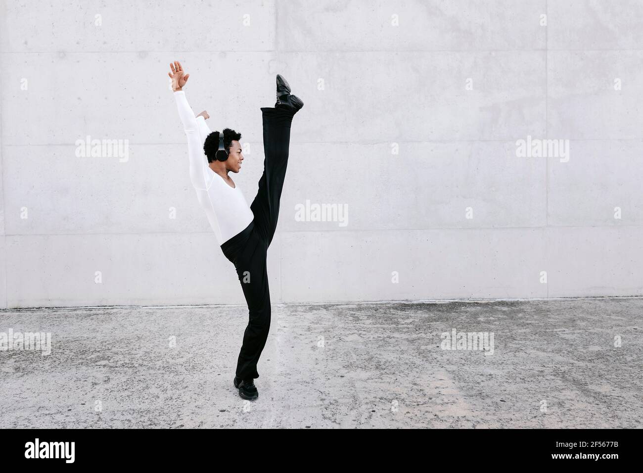 Flexible male dancer stretching leg while practicing urban dance ...