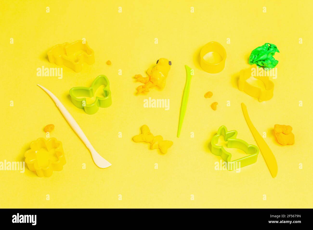 Colorful modeling clay, tools, and forms isolated on yellow background ...