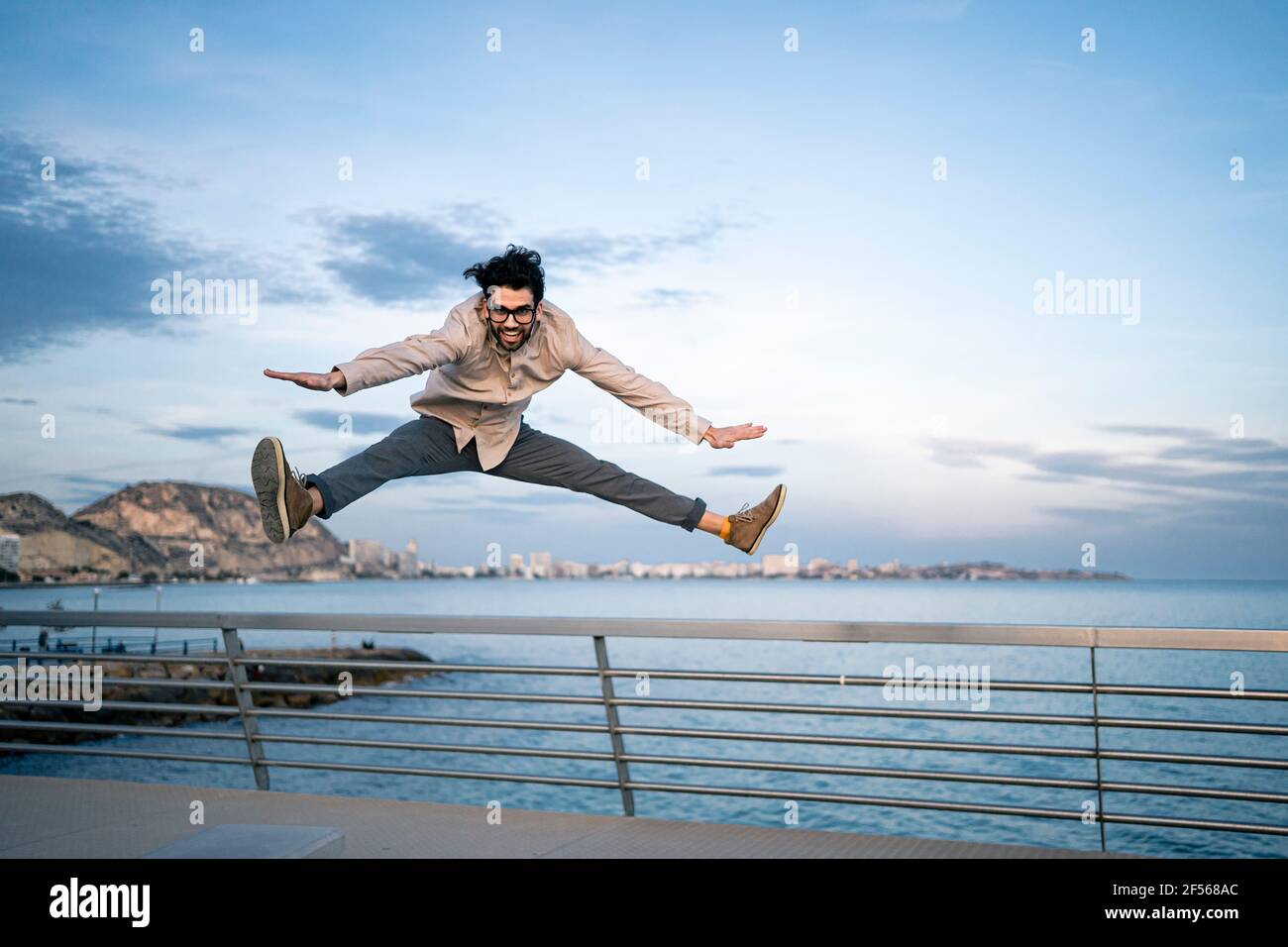 Male business professional with arms outstretched doing splits in mid ...