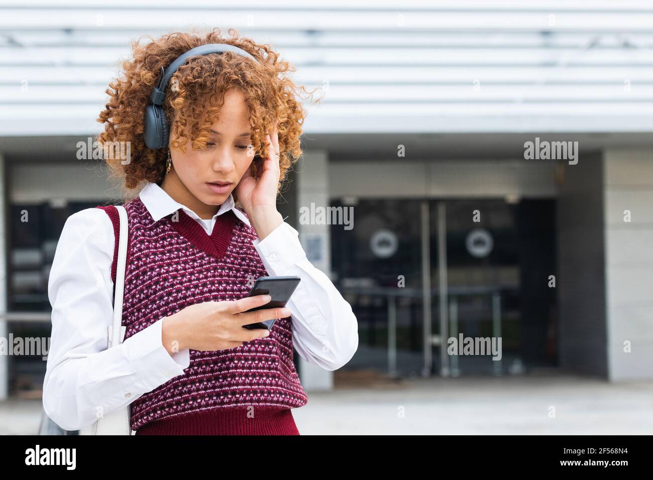 Woman with headphones using mobile phone while standing outdoors Stock ...