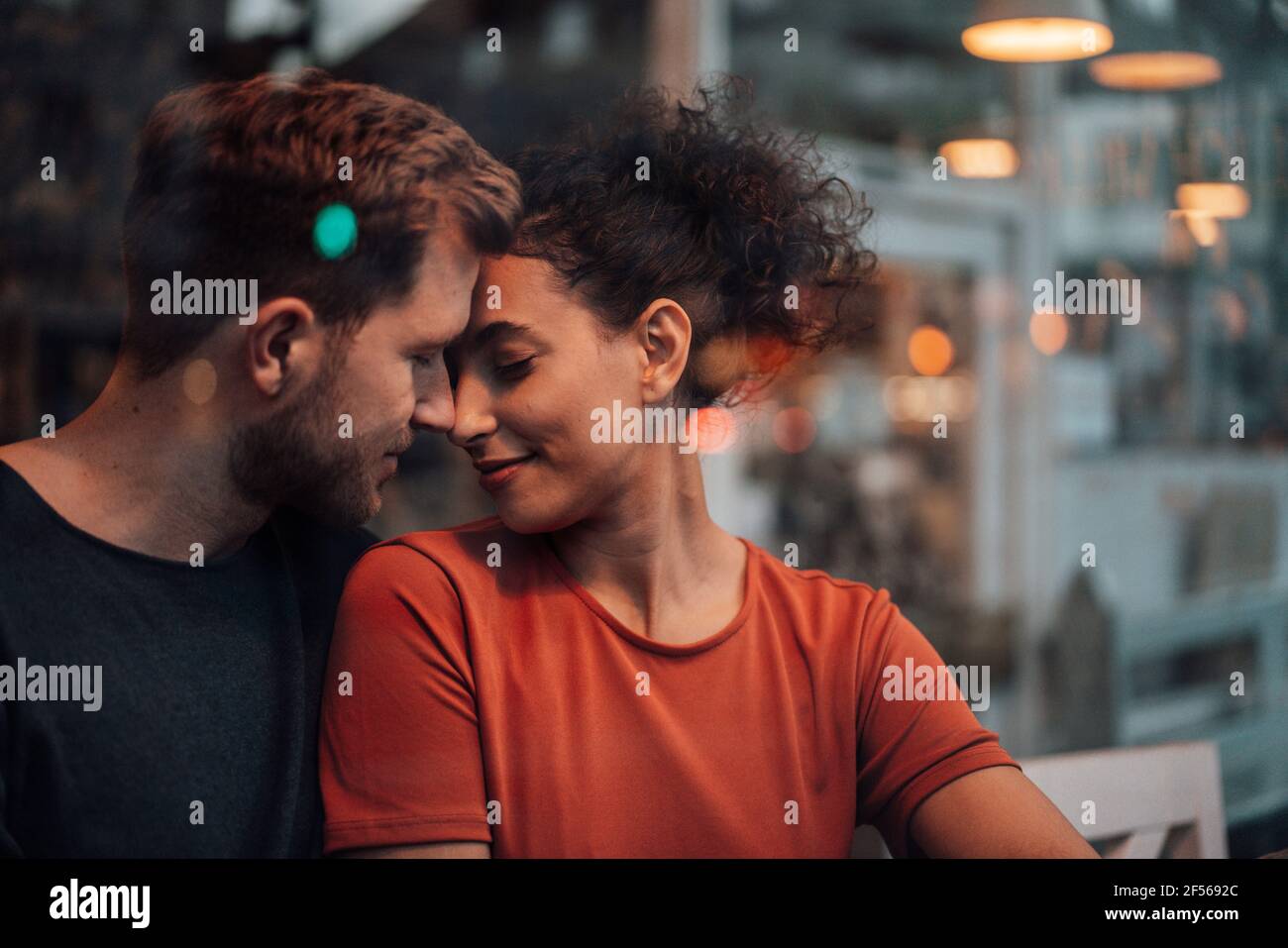 Romantic couple with eyes closed sitting face to face at cafe Stock ...